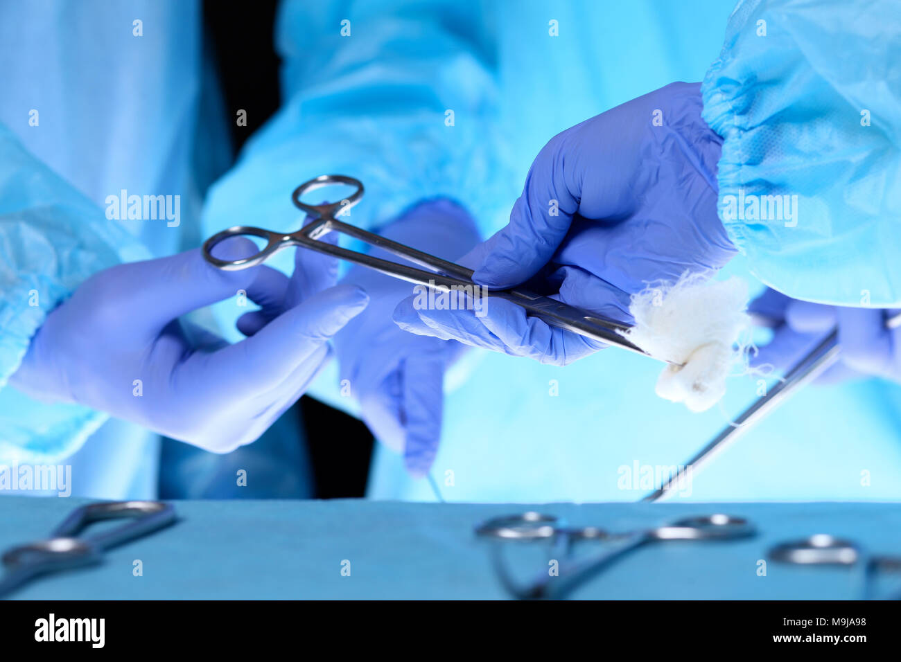 Surgeons hands holding surgical scissors and passing surgical equipment ...