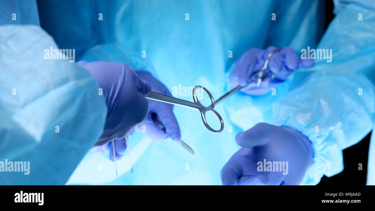 Surgeons hands holding surgical scissors and passing surgical equipment ...
