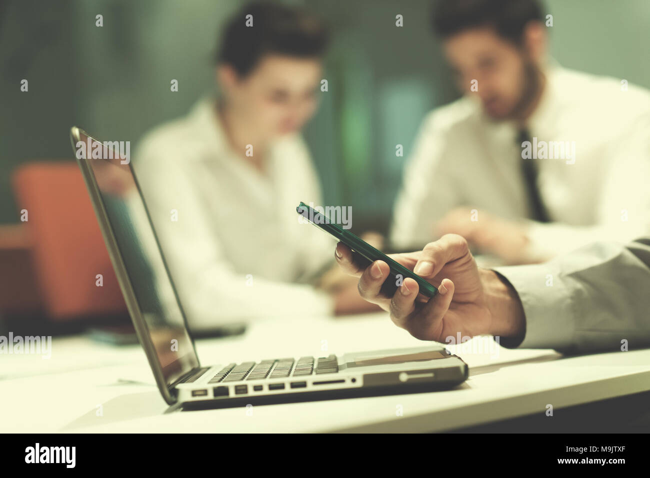 close up of businessman hands using smart phone and laptop computer ...