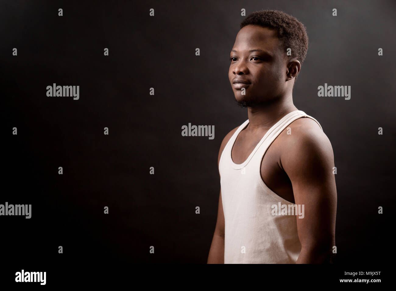 side view shot of muscular young man wearing white vest. youth Stock ...