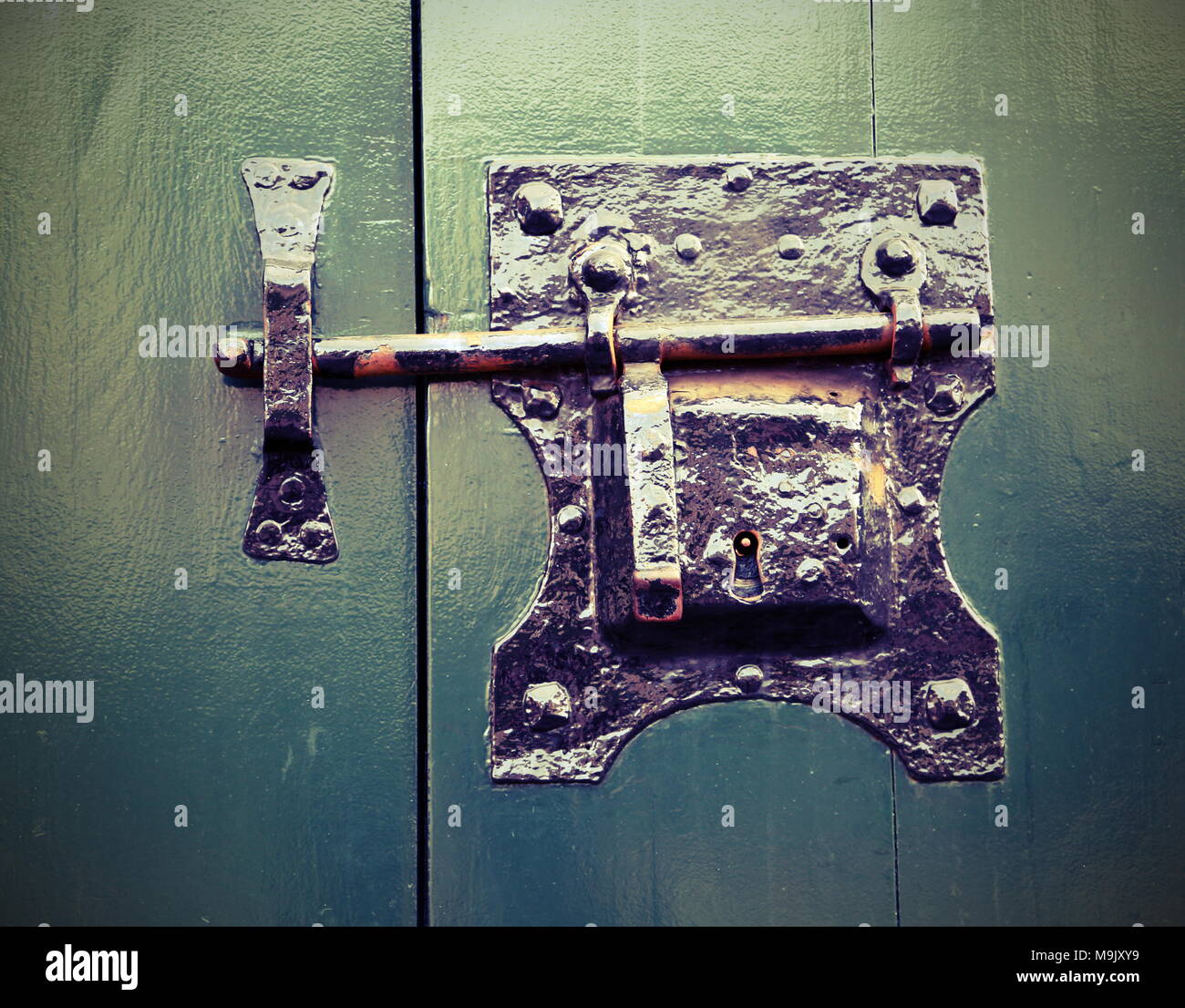 ancient solid iron lock in a green door Stock Photo - Alamy