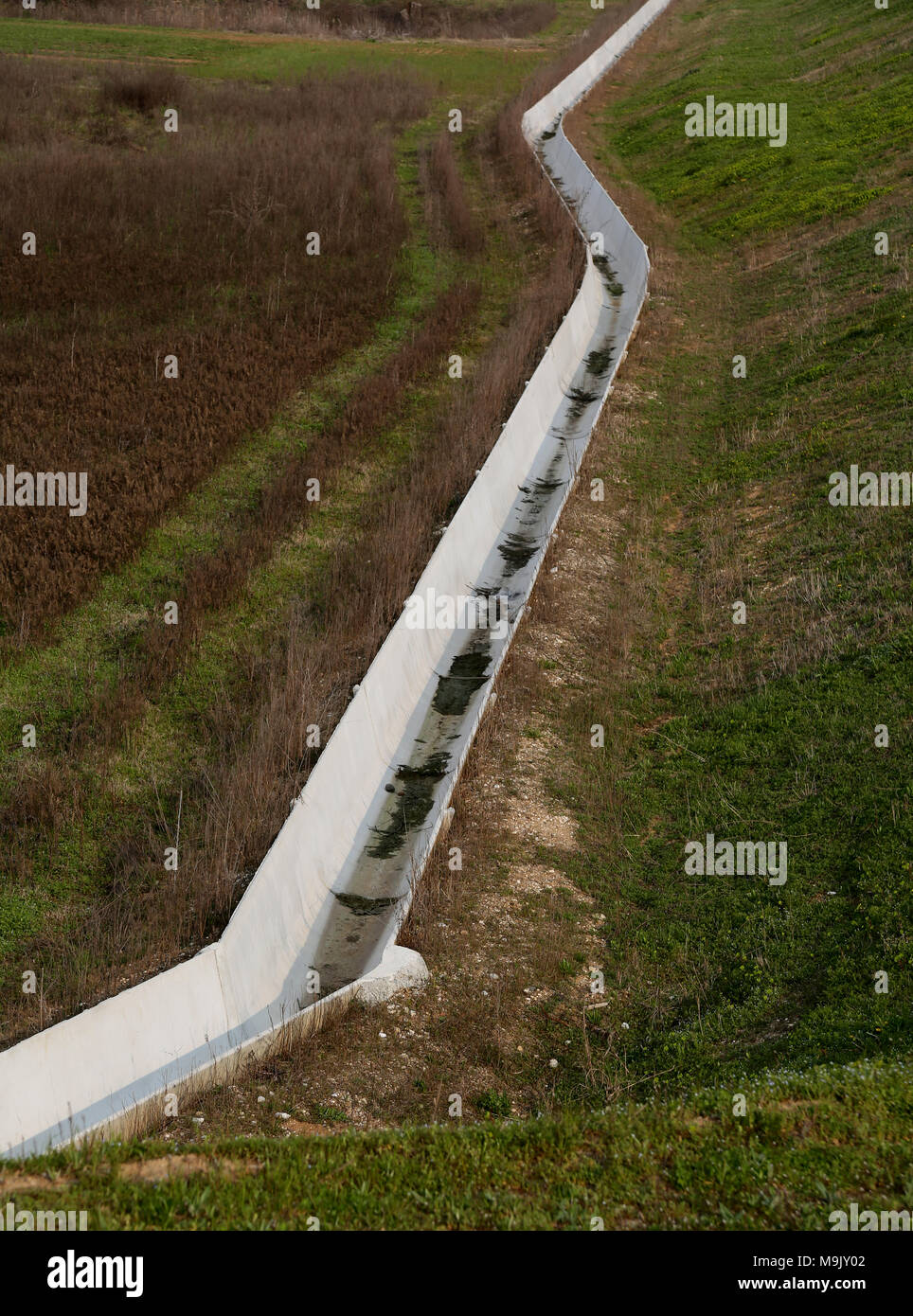 white concrete ditch on the field to transport water for irrigation ...
