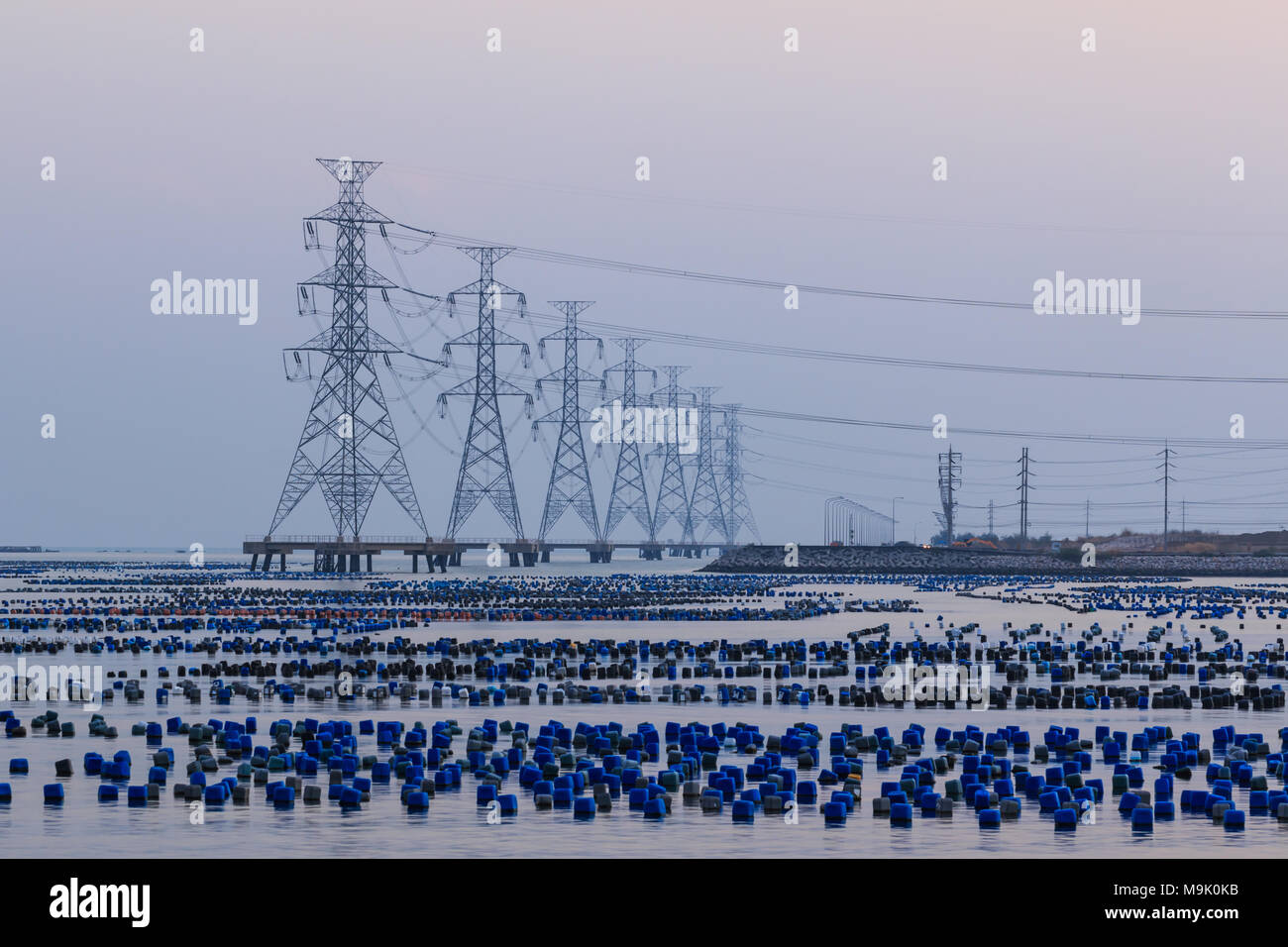 Row of high voltage poles and many tanks floating above the sea Stock ...