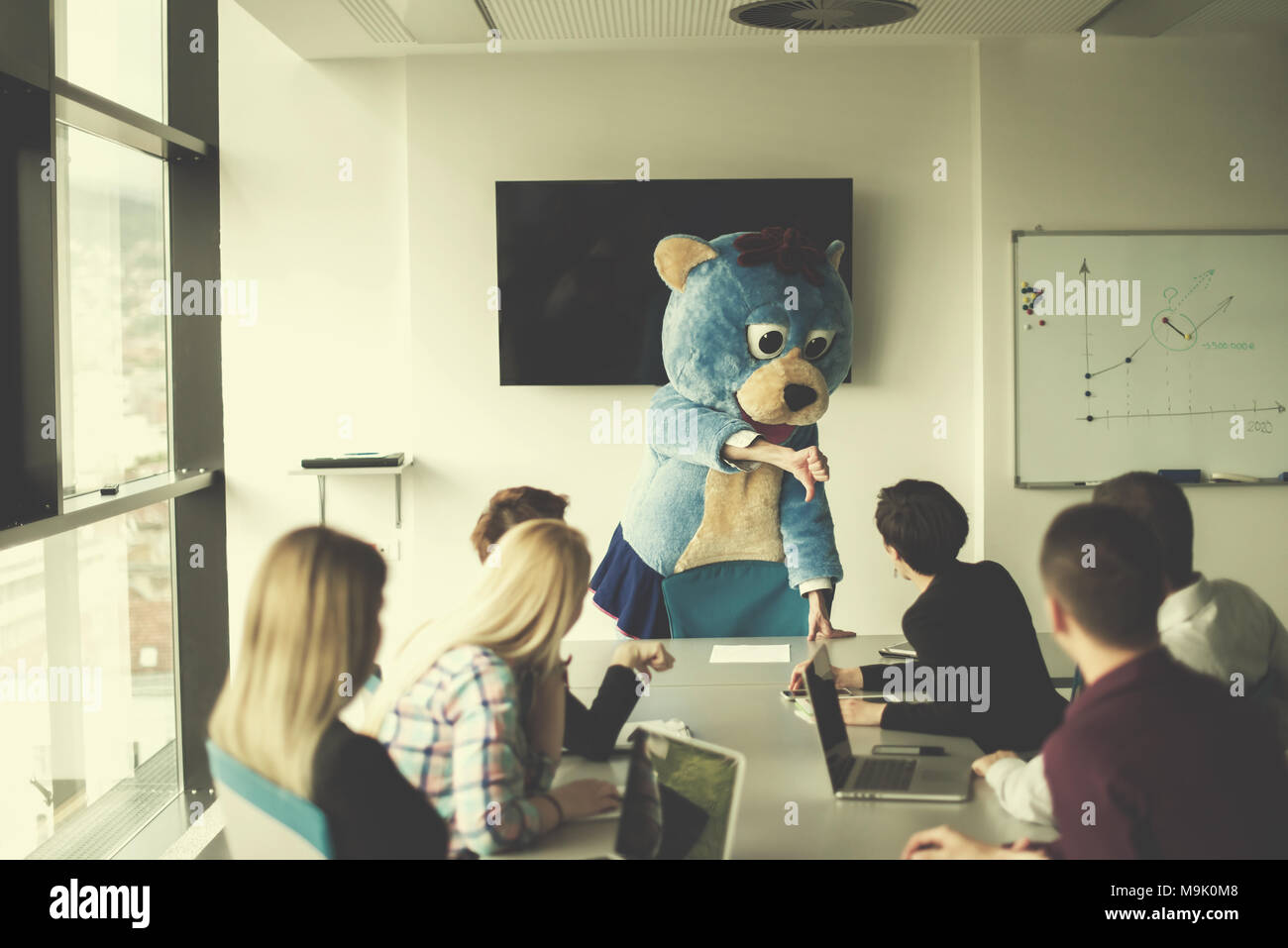 Boss dresed as teddy bear having fun with bussines people in modern ...