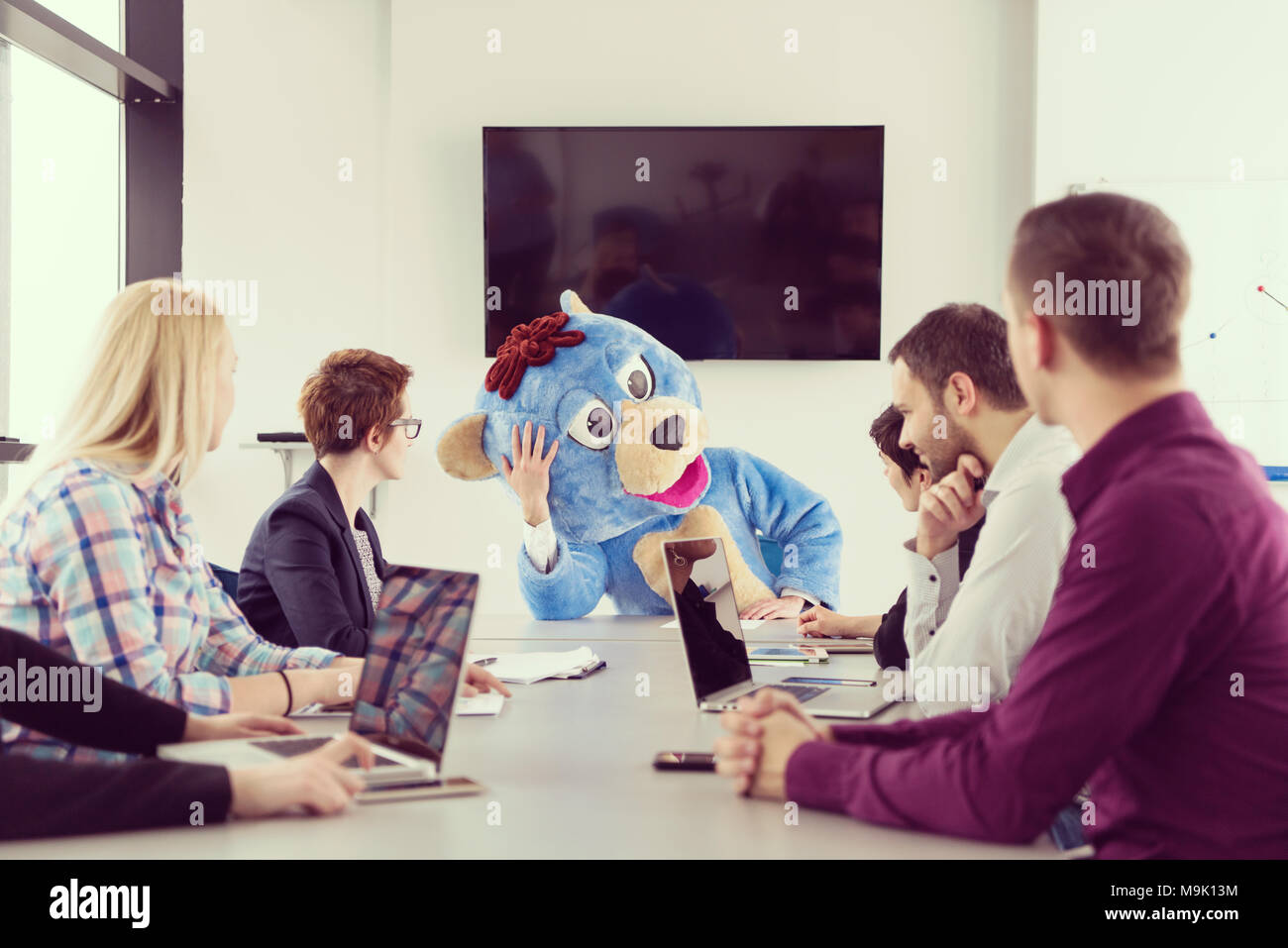 Boss dresed as teddy bear having fun with bussines people in modern ...