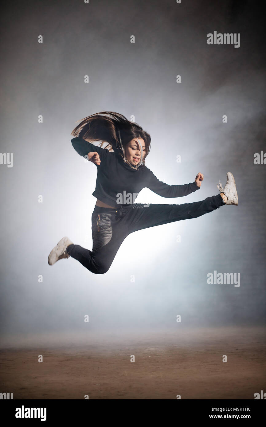 young sportswoman is jumping bending one leg outdoor. jumping exersise ...