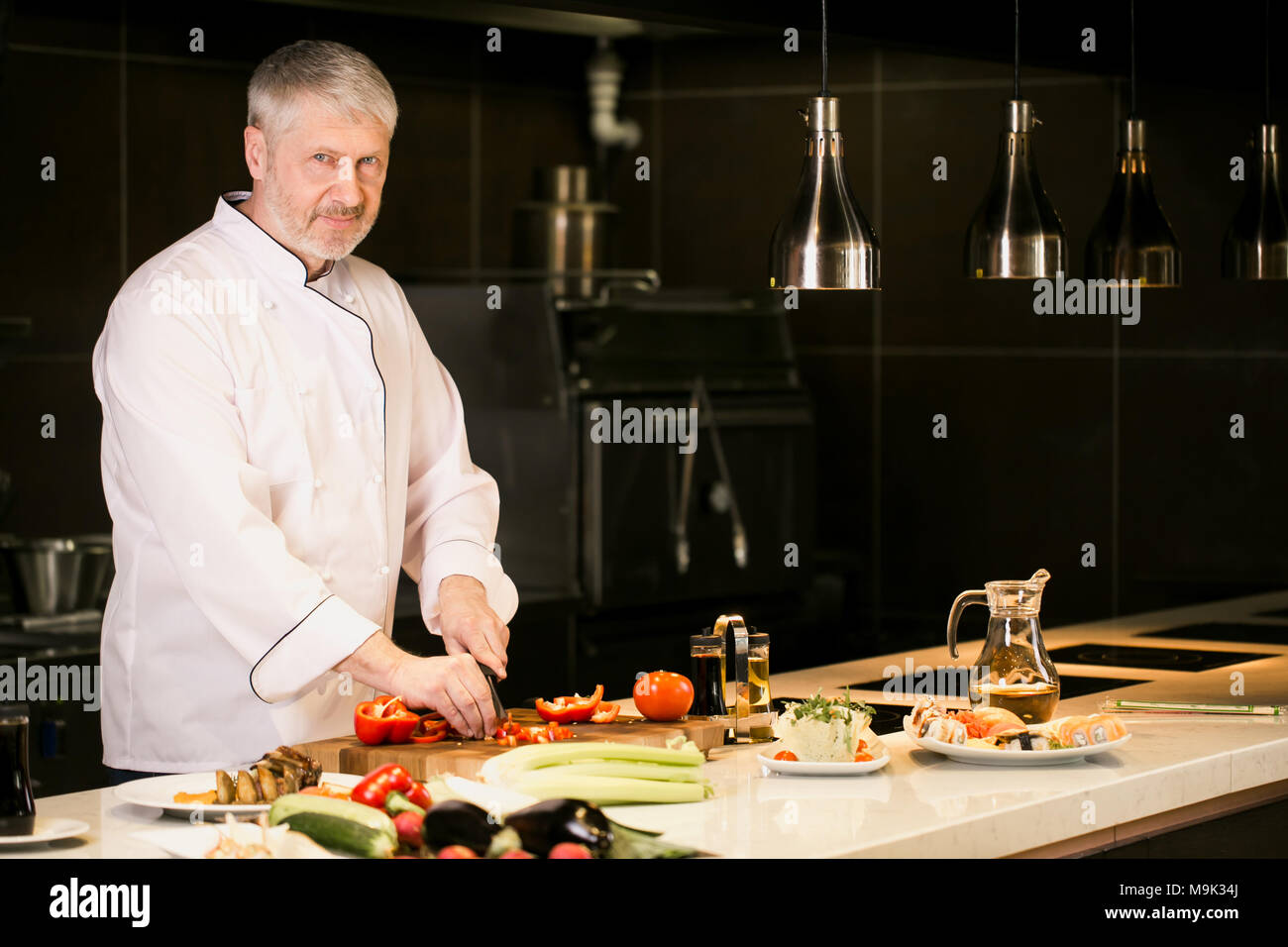handsome old cook with grey hair, moustage and beard fixing a meal ...