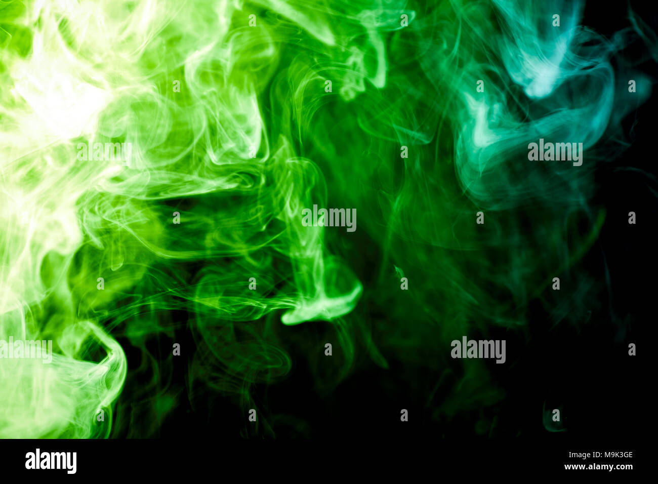 Dense multicolored smoke of green colors on a black isolated background ...