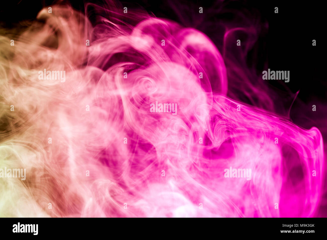 Thick colorful smoke of pink and red on a black isolated background ...