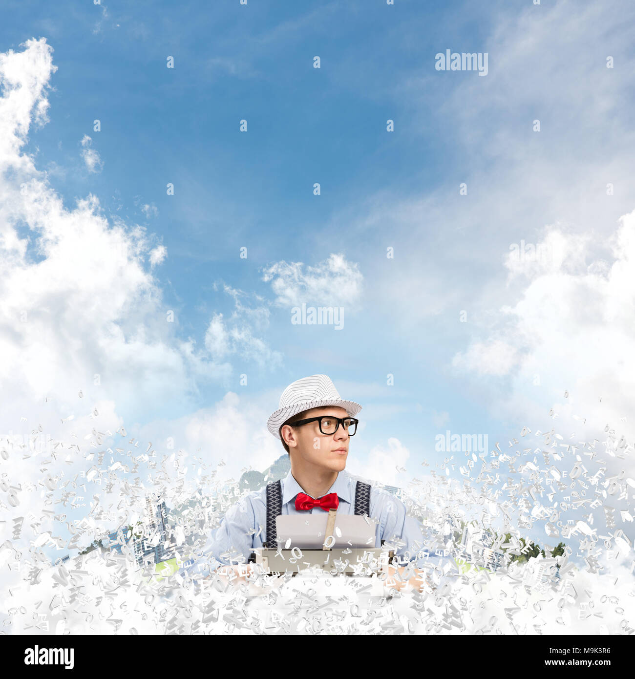 Young man writer in hat and eyeglasses using typing machine while ...