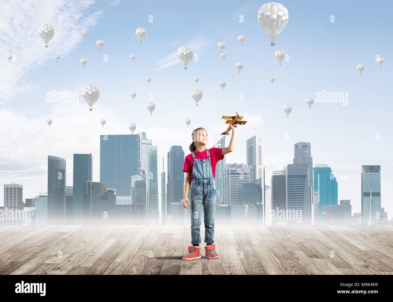 Cute kid girl standing on wooden floor and aerostats flying in air ...