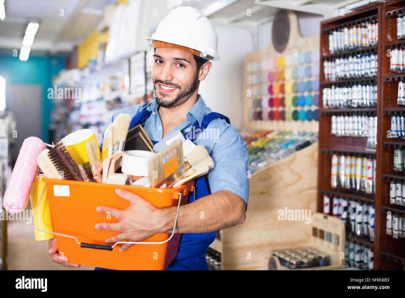 Happy cheerful smiling workman holding basket with picked tools in ...