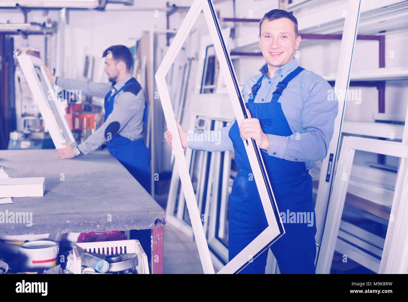 Smiling production workers in coverall with different PVC windows and ...