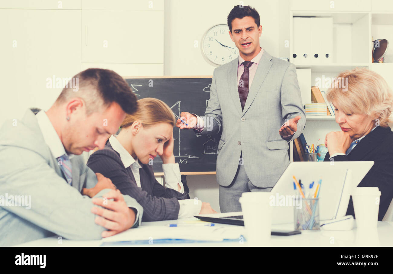 Businessman feeling angry to coworkers in office, pointing at diagrams ...