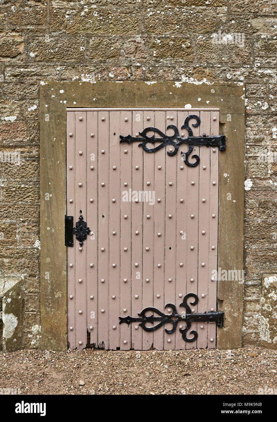 A studded wooden door with ornate Iron Hinges at the side of Panbride ...