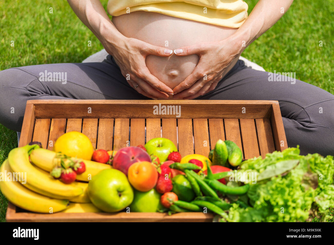 Pregnant woman sitting on grass and holding an apple in hand Stock ...