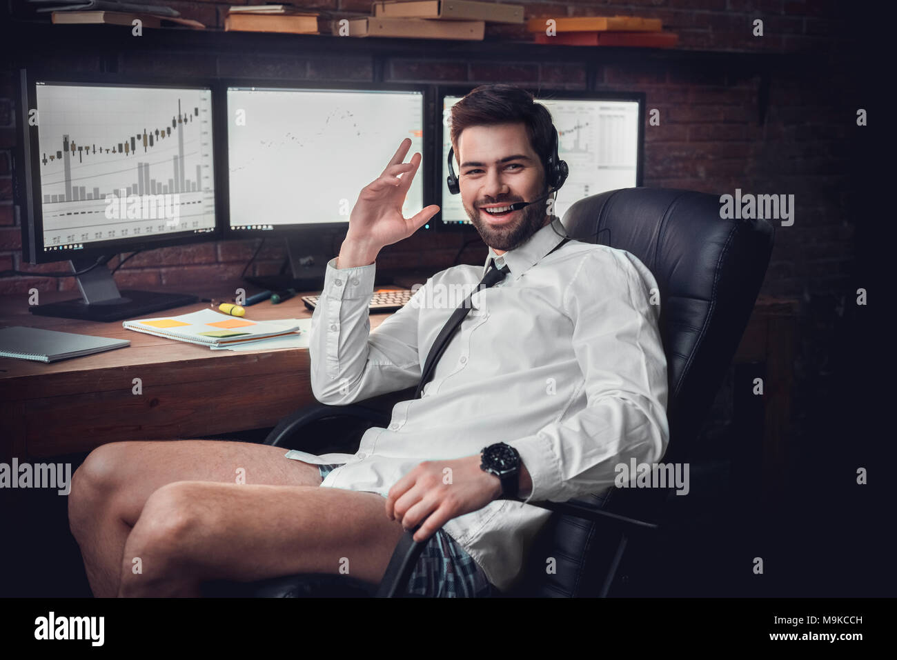 Funny trader in headset underpants looking at camera working at home on ...