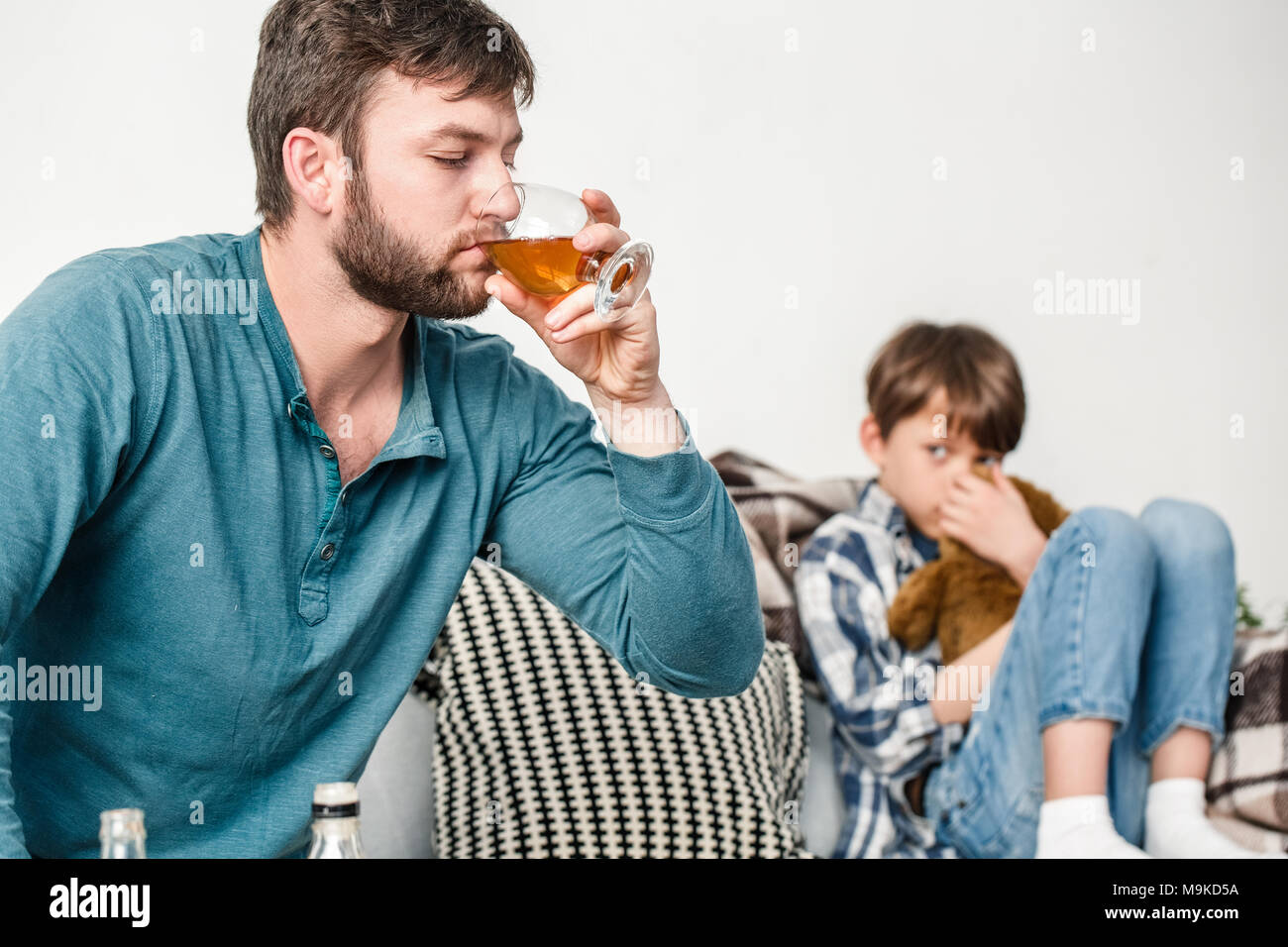 Boy and father alcoholic at home man drinking whiskey joyful close-up ...