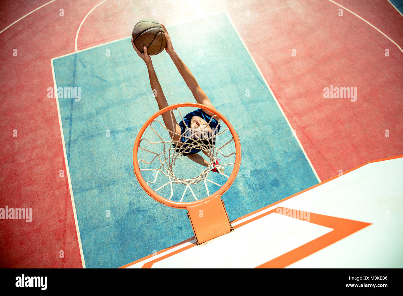 Young man jumping and making a fantastic slam dunk playing streetball ...