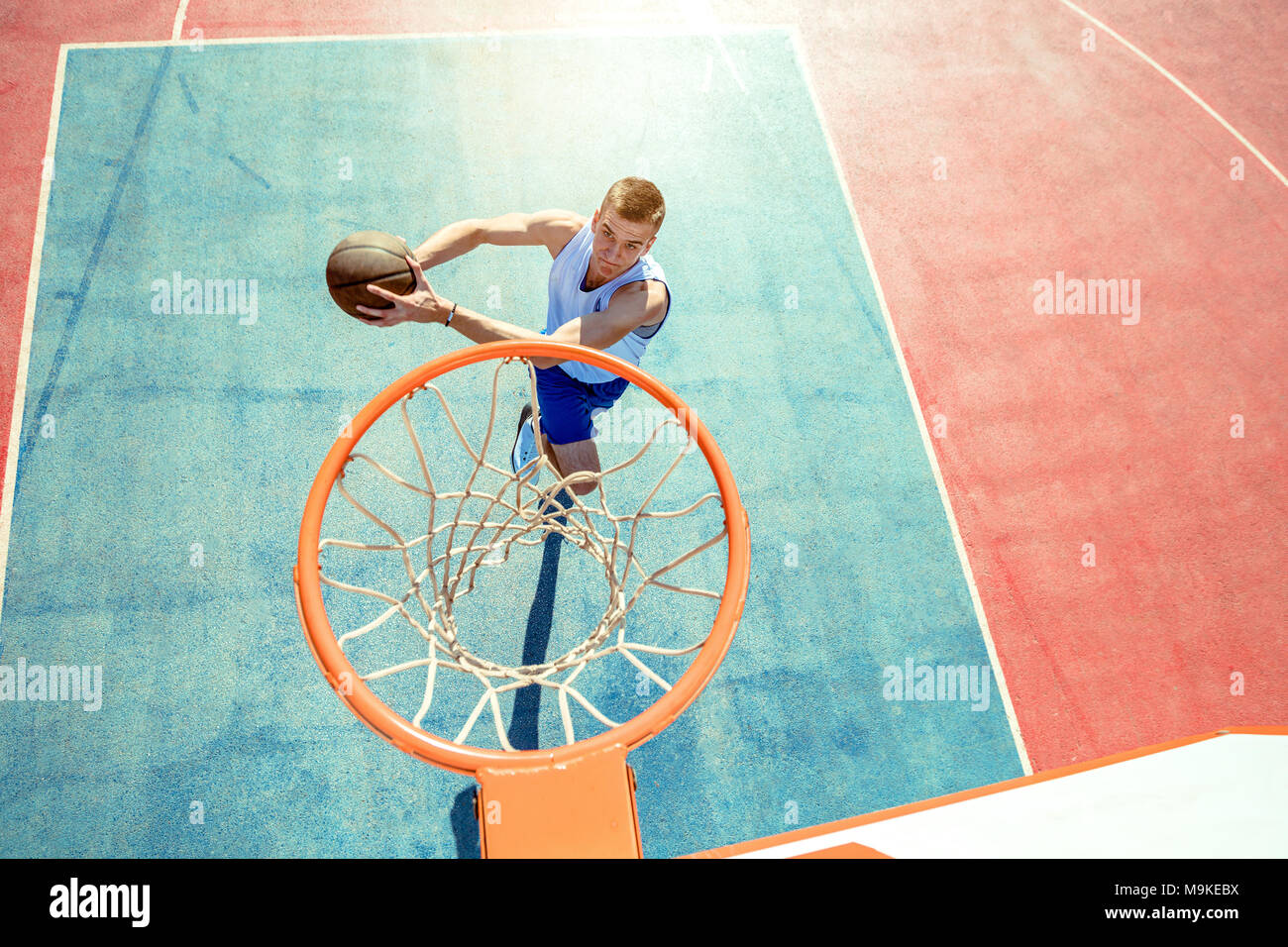 Young man jumping and making a fantastic slam dunk playing streetball ...