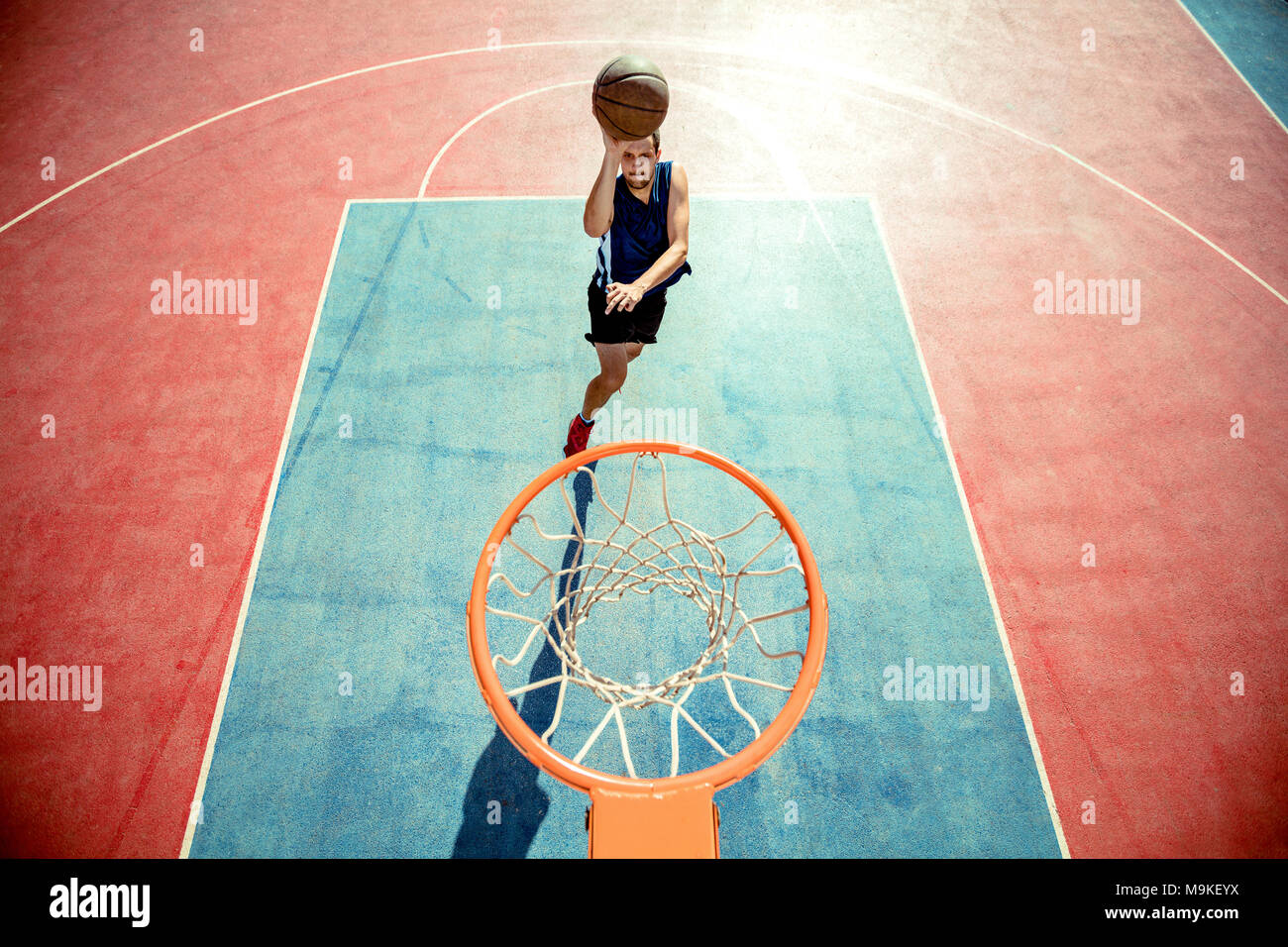 Young man jumping and making a fantastic slam dunk playing streetball ...