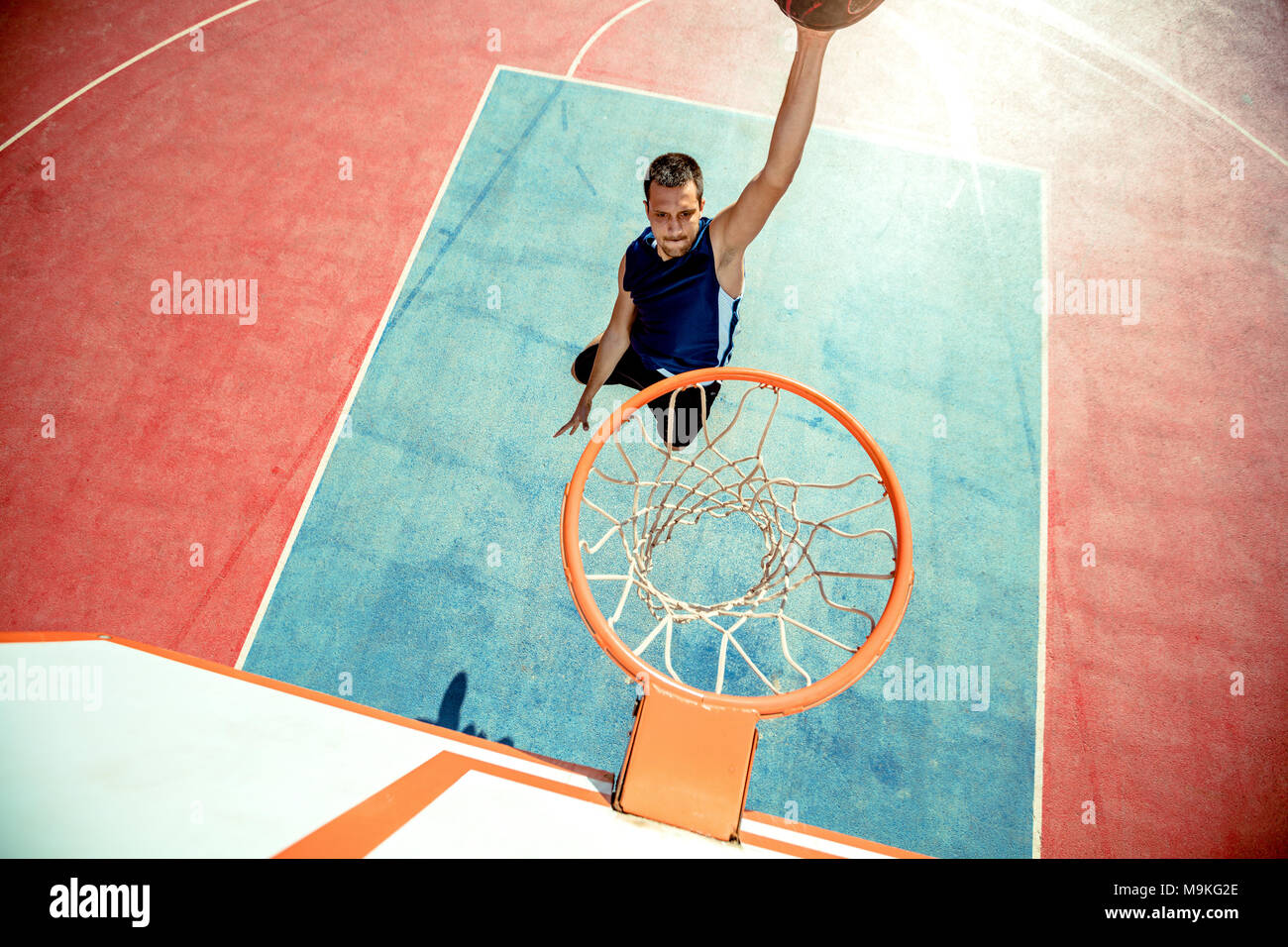 Young man jumping and making a fantastic slam dunk playing streetball ...