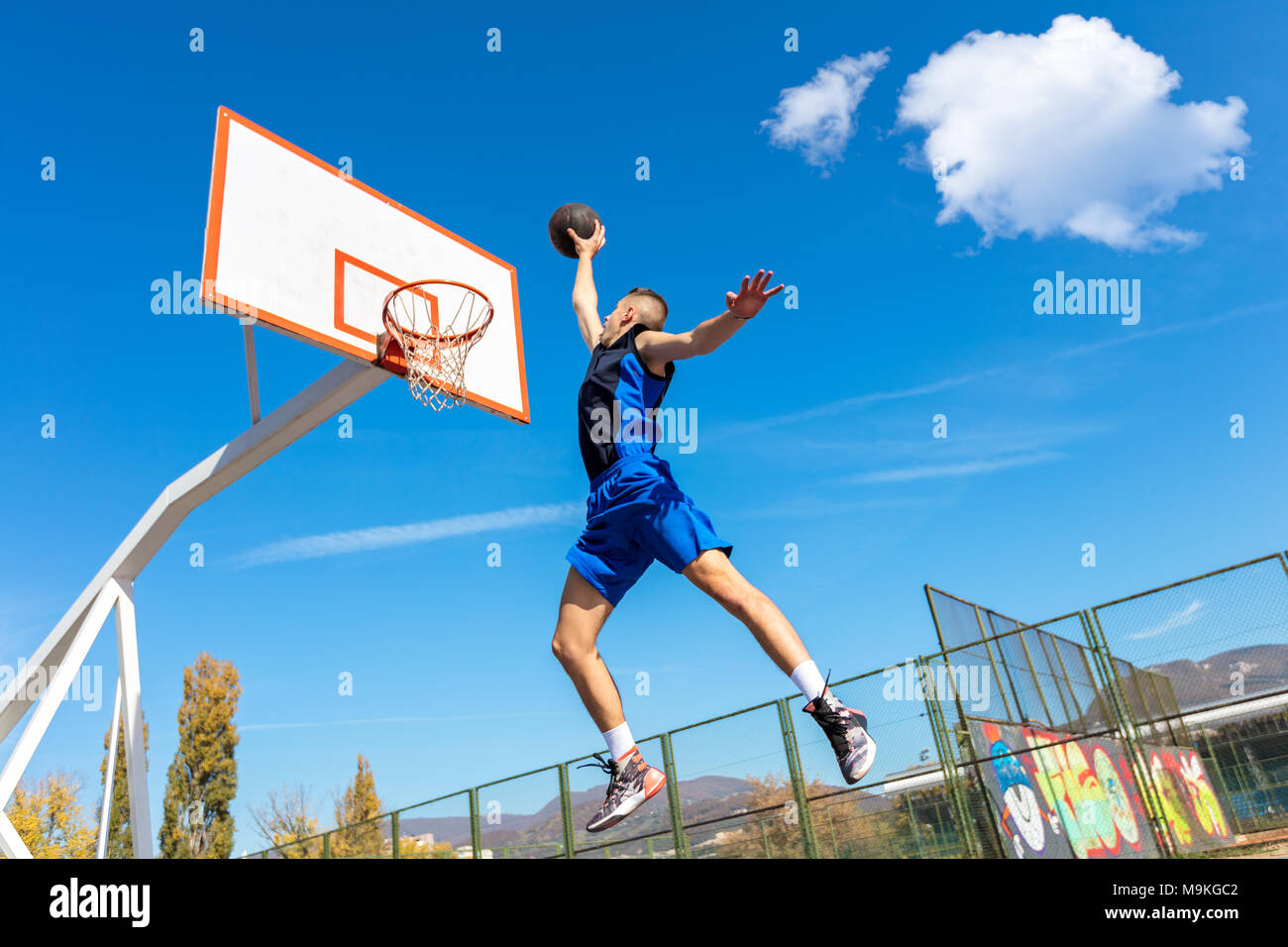 Young Basketball street player making slam dunk Stock Photo - Alamy