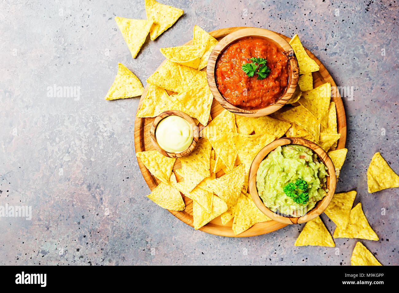 Mexican nachos with guacamole, salsa and cheese dip in wooden bowls on ...