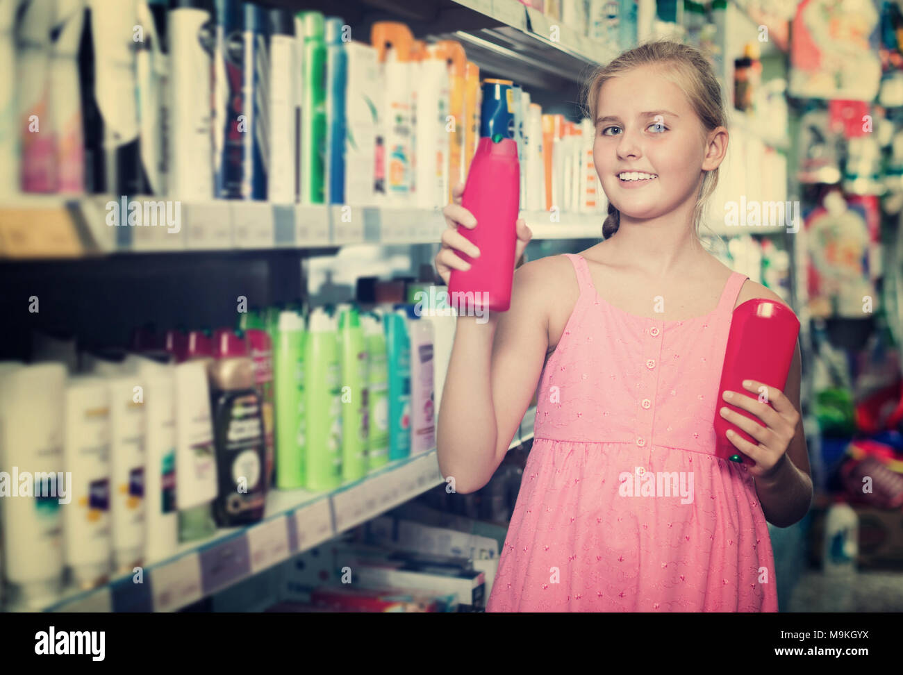 Portrait of smiling girl holding shampoo and conditioner in the hand in ...
