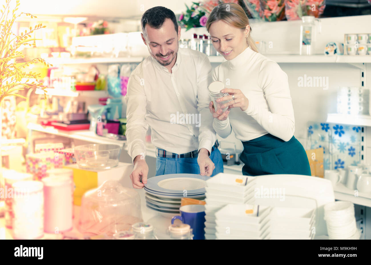 Young glad couple choosing new crockery in dinnerware store Stock Photo ...