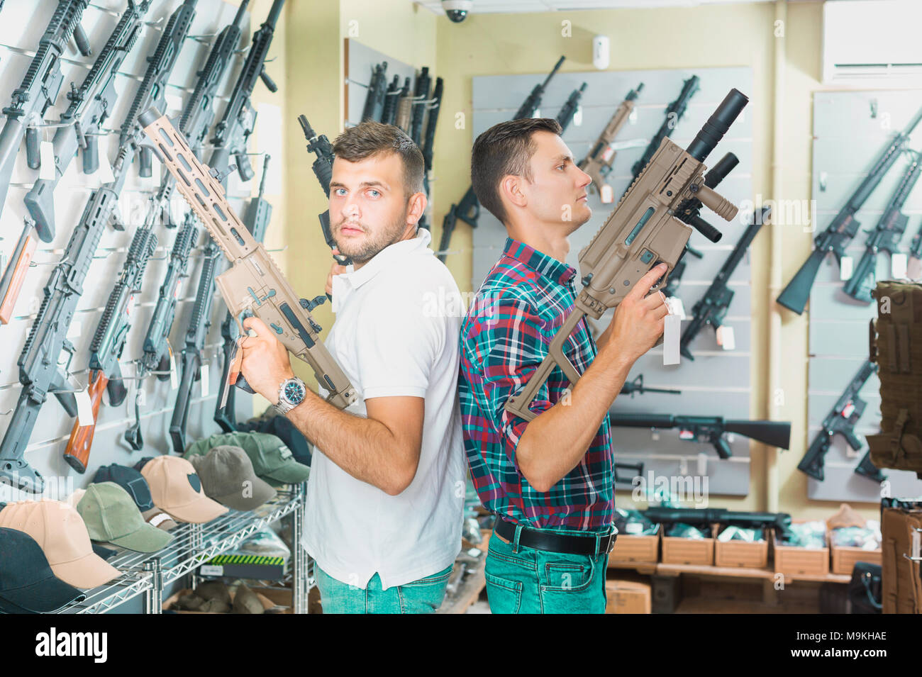 Male friends choosing air-powered gun in army market Stock Photo - Alamy