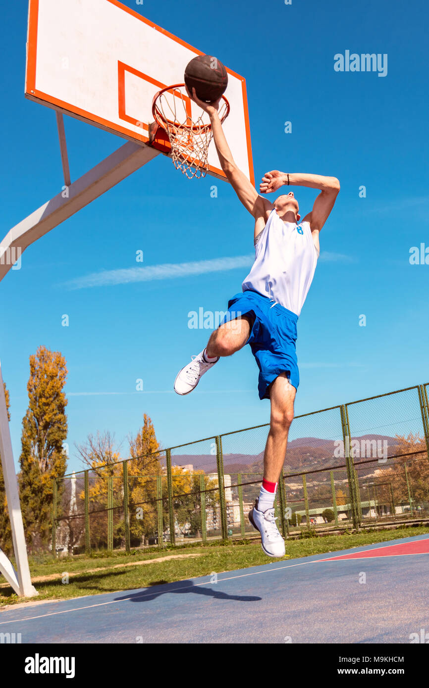 Young Basketball street player making slam dunk Stock Photo - Alamy