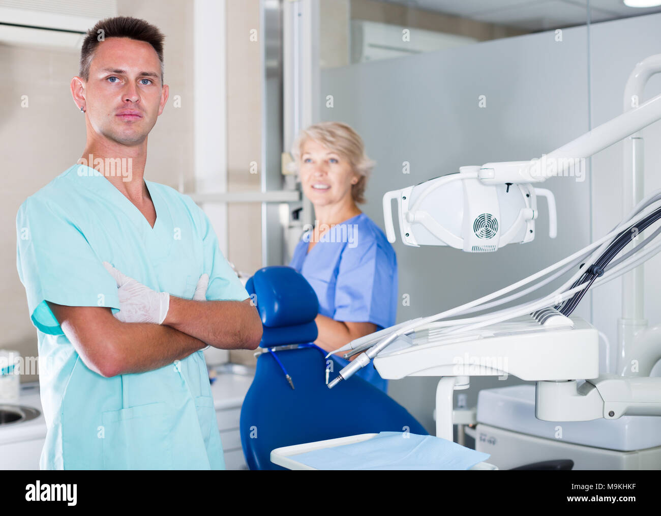 Portrait of professional male dentist with arms crossed with dental ...