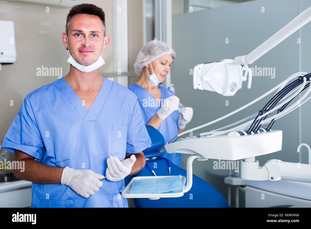 Professional smiling dentist standing in dental office with dental ...