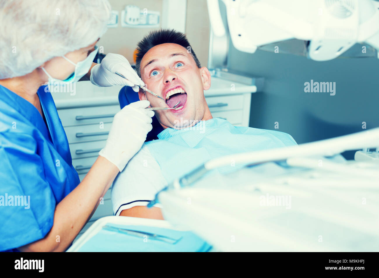 Male patient sitting on chair in dental office getting dentist ...