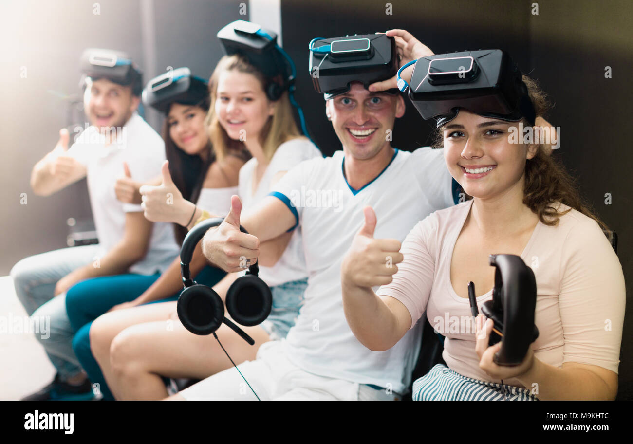 Group of friends are wearing virtual reality goggles and giving thumbs ...