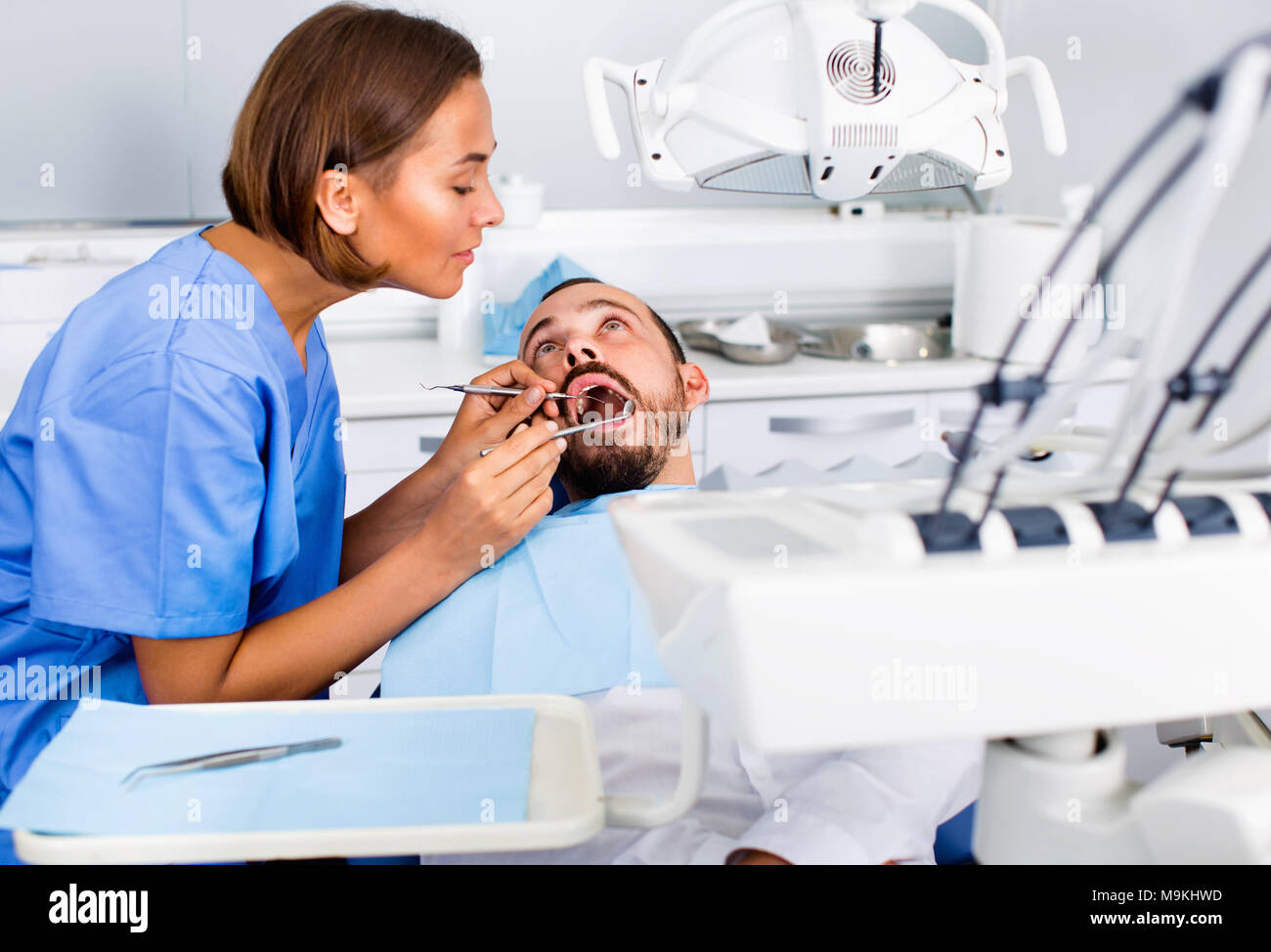 Smiling stomatologist girl in uniform is taking visional inspection of ...