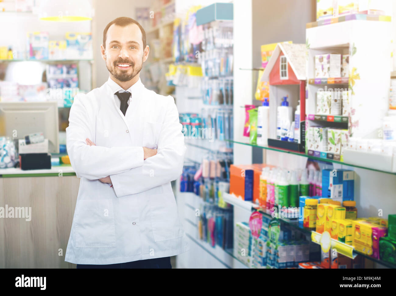 Happy male pharmacist demonstrating assortment of drugs in pharmacy ...