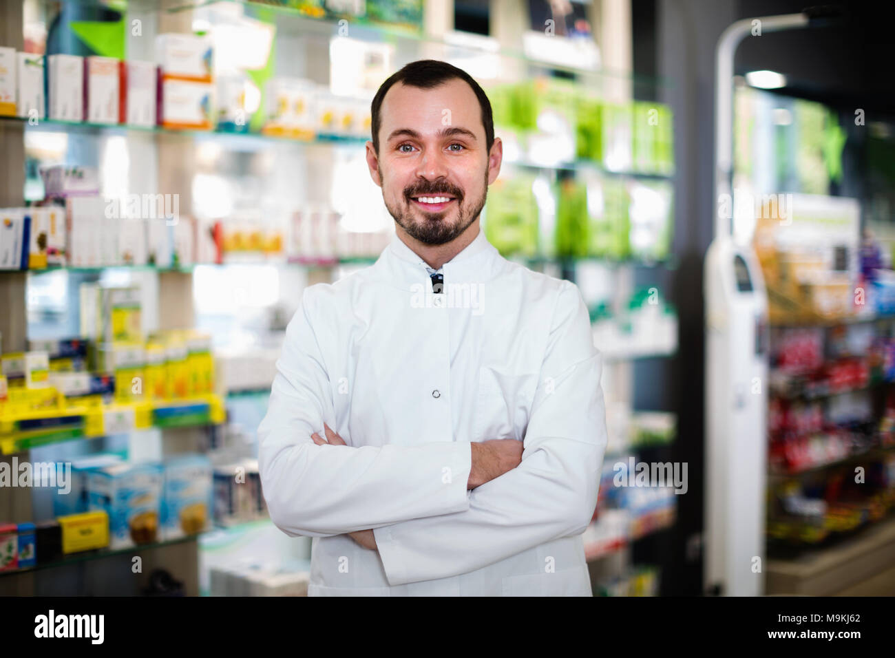 Smiling happy male pharmacist demonstrating assortment of drugs in ...