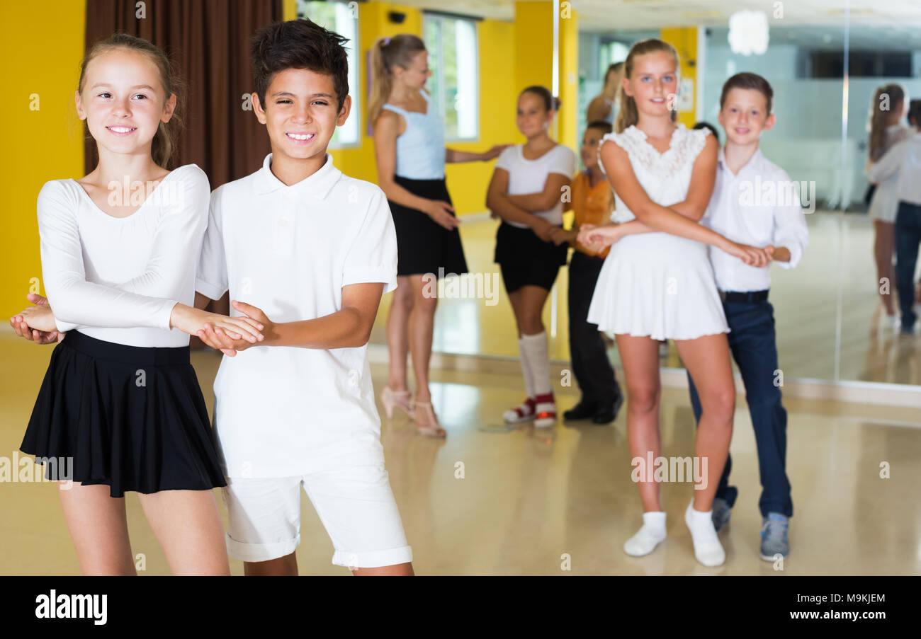 Happy boys and girls dancing in studio with young female coach and ...