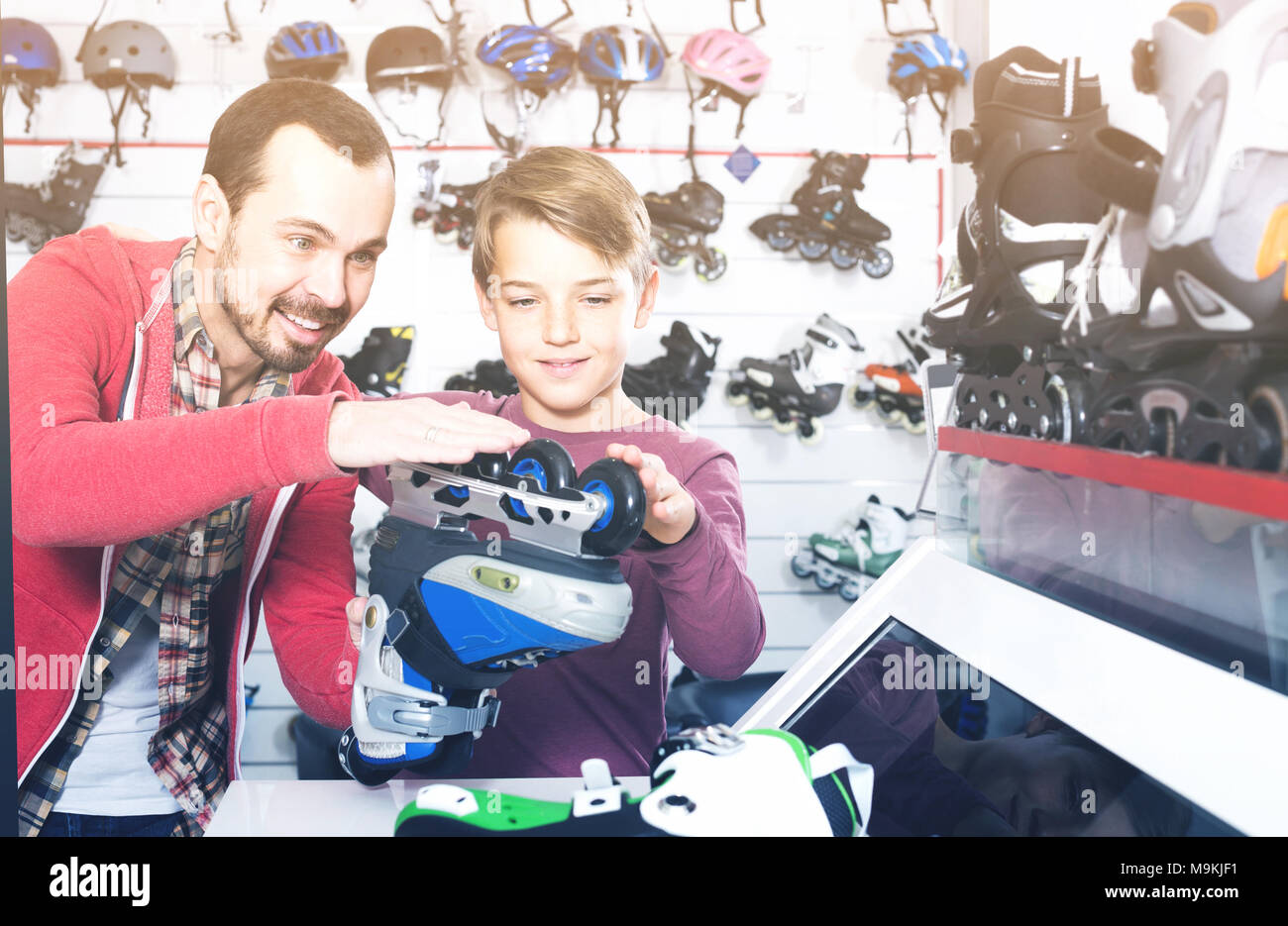positive russian father and son deciding on new roller-skates in sports ...