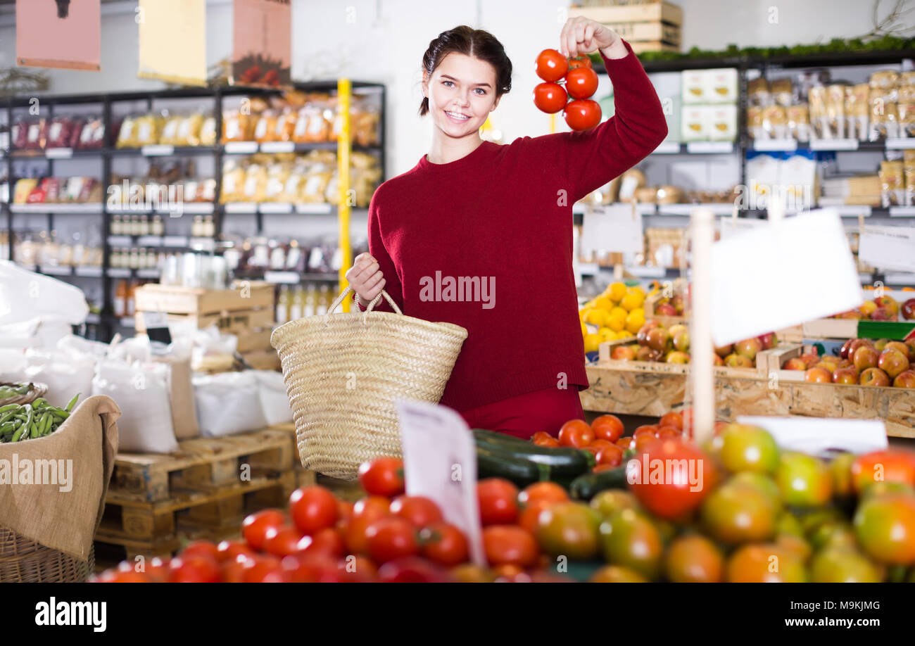 Young woman showing a large twig with tomatoes in the store Stock Photo ...