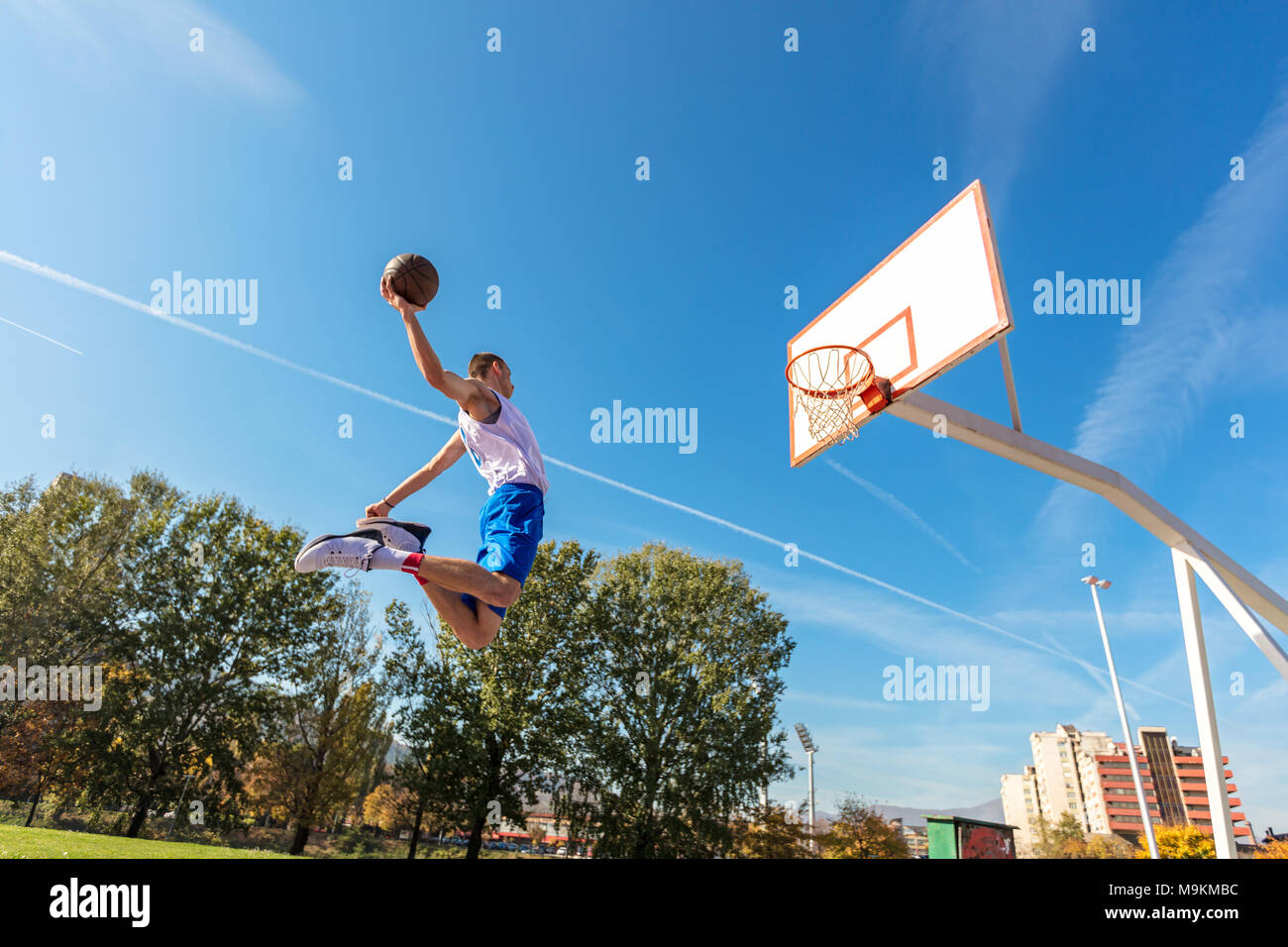 Young Basketball street player making slam dunk Stock Photo - Alamy