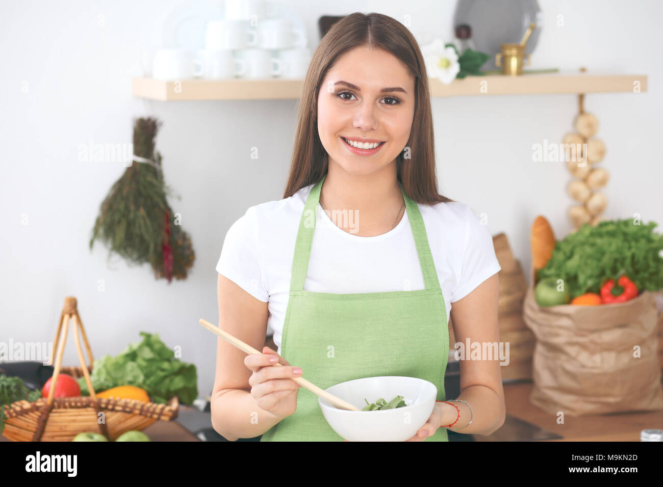 Young happy woman cooking in the kitchen. Healthy meal, lifestyle and ...