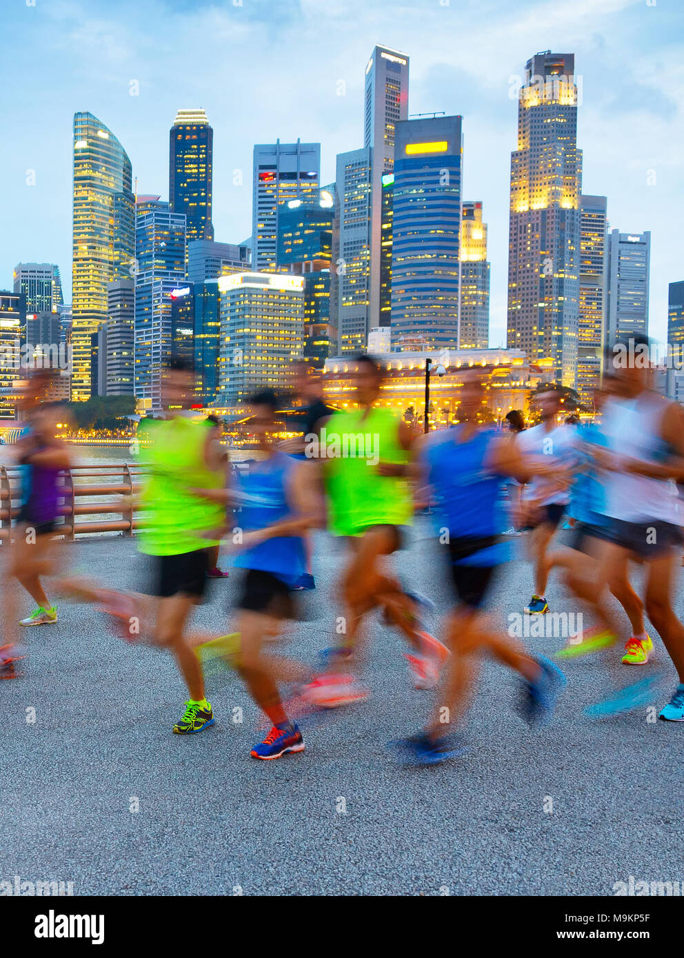 Group of runners on Singapore quayside at dusk, Singapore Downtown in ...