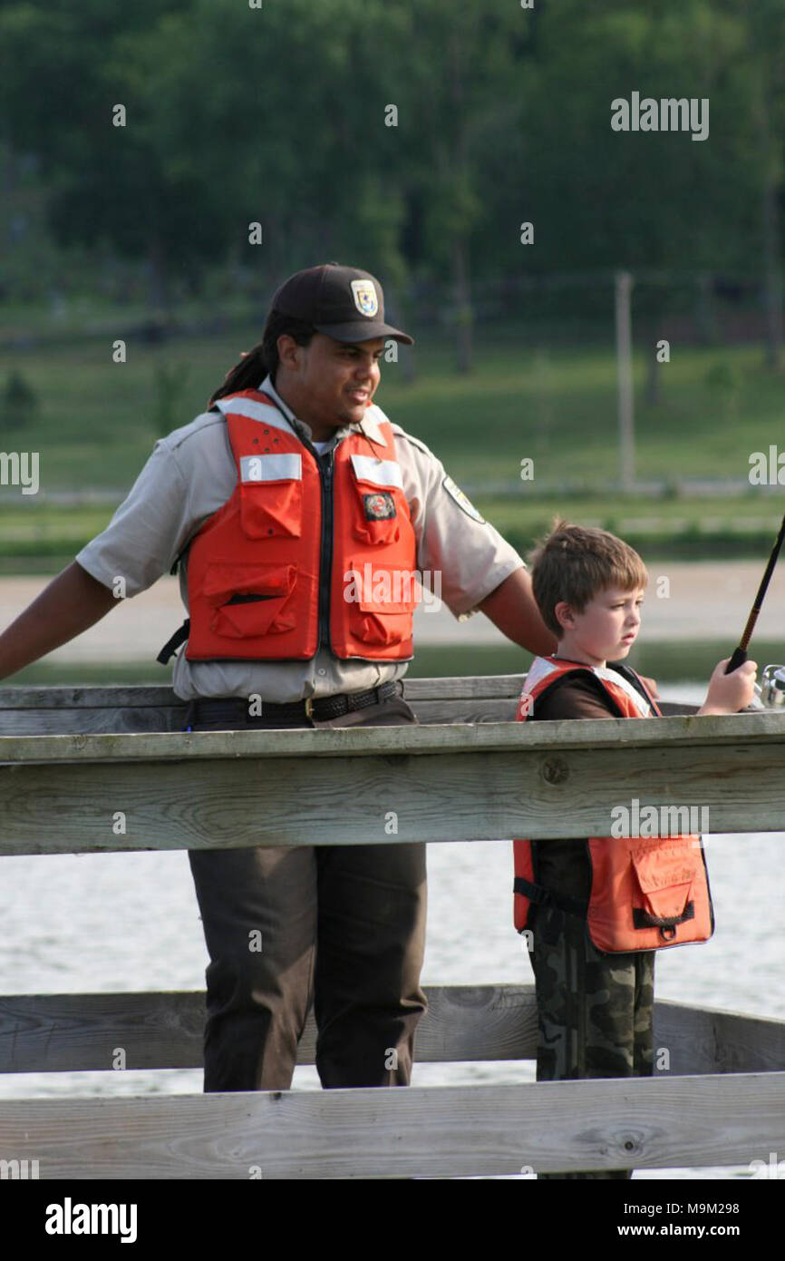 Park Ranger Lewis Johnson assists a young angler during a fishing event ...