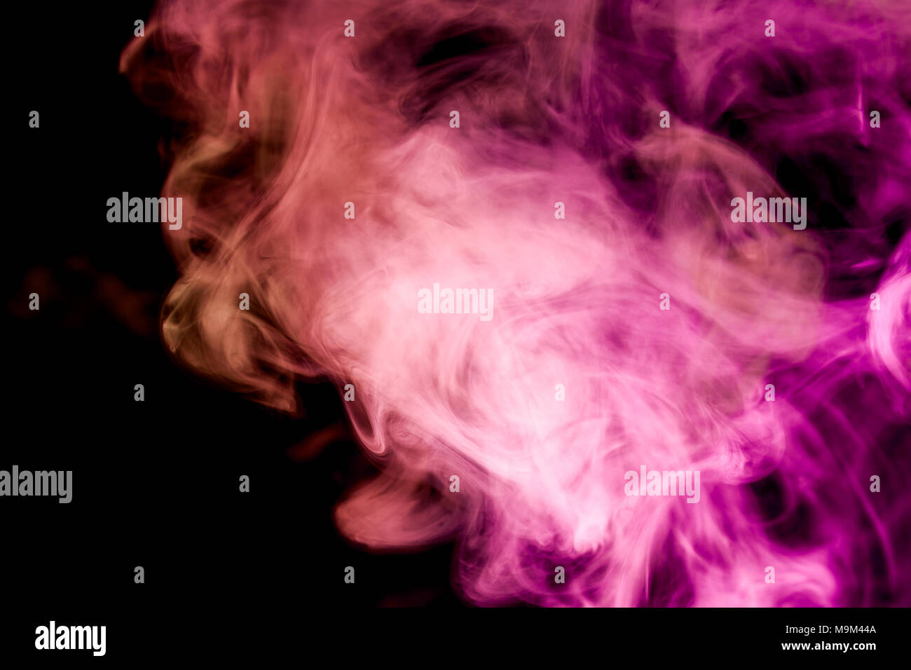 Thick colorful smoke of pink and red on a black isolated background ...
