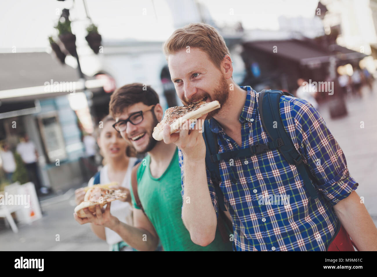 Happy students eating pizza on street Stock Photo - Alamy