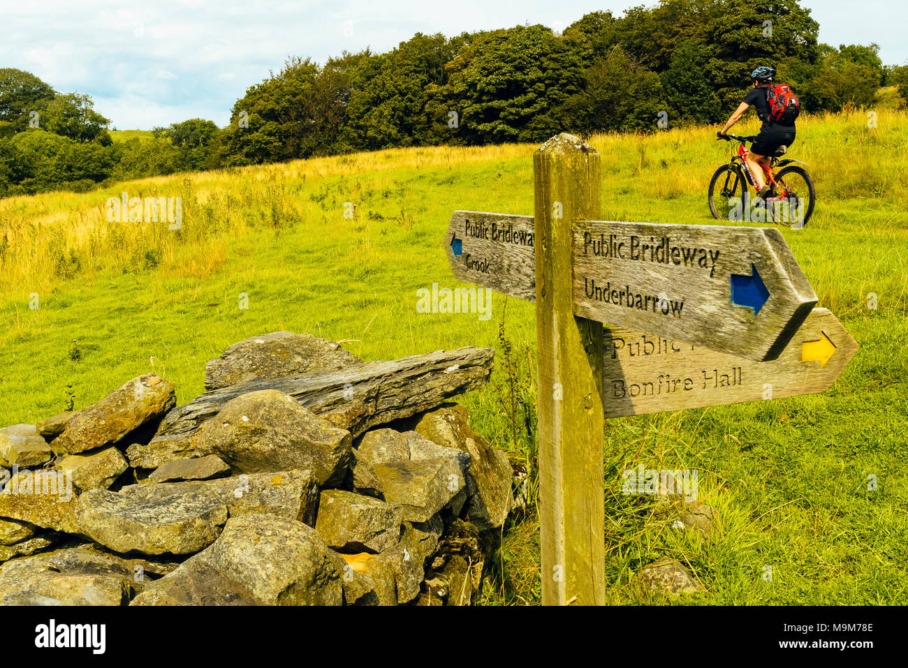 Mountain biker passing right of way signs in countryside west of Kendal ...