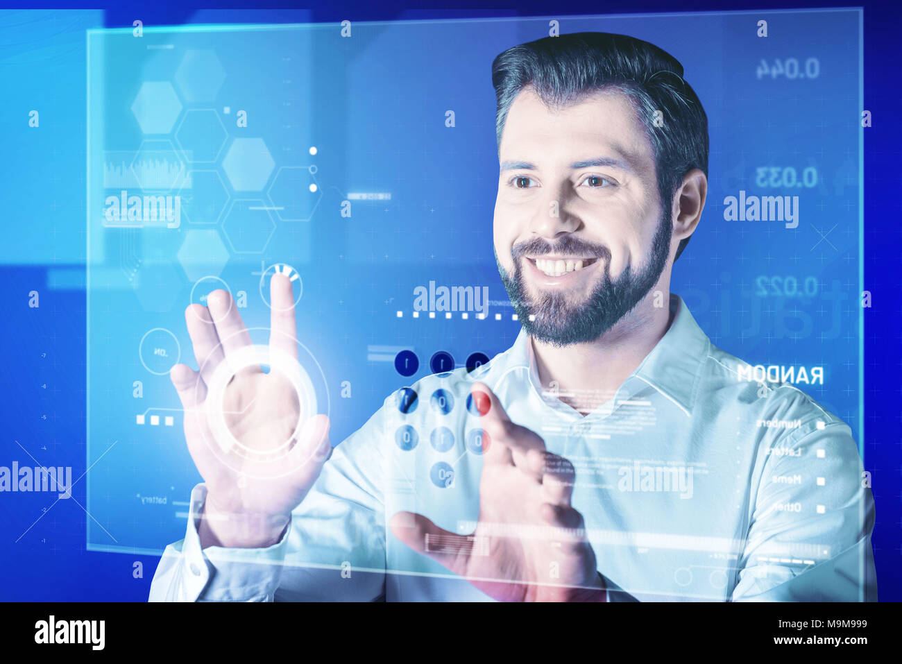 Bearded young man smiling while touching a futuristic transparent ... Bearded young man smiling while touching a futuristic transparent ...